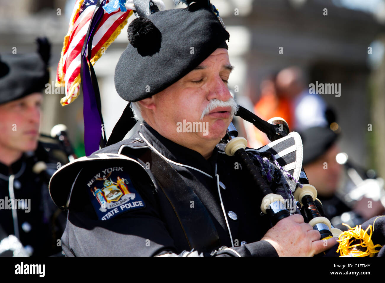 A New York State Police Pipe and Drum Corps member lets out a sigh of ...