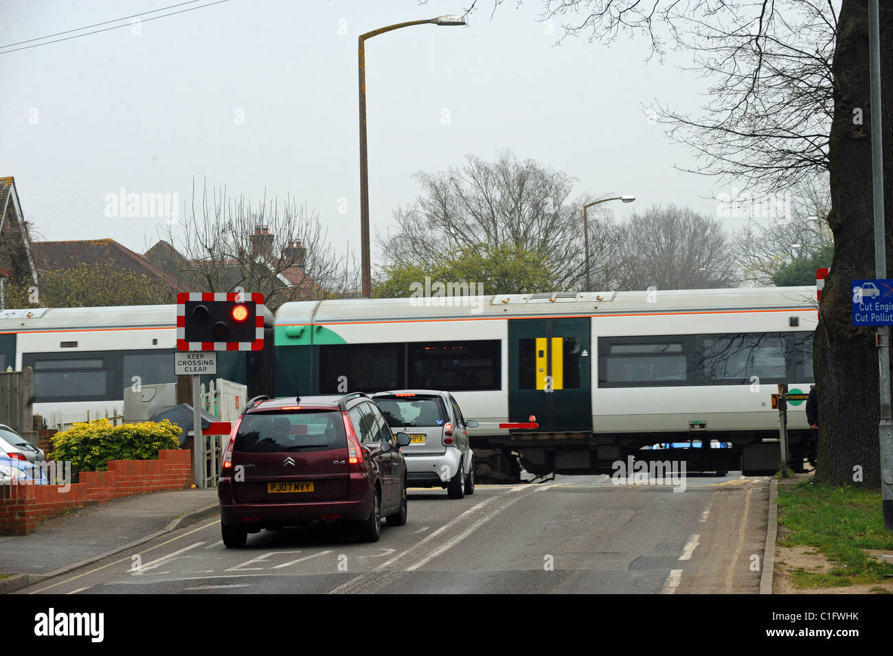Railway crossing barrier with train travelling past at road Horsham ...