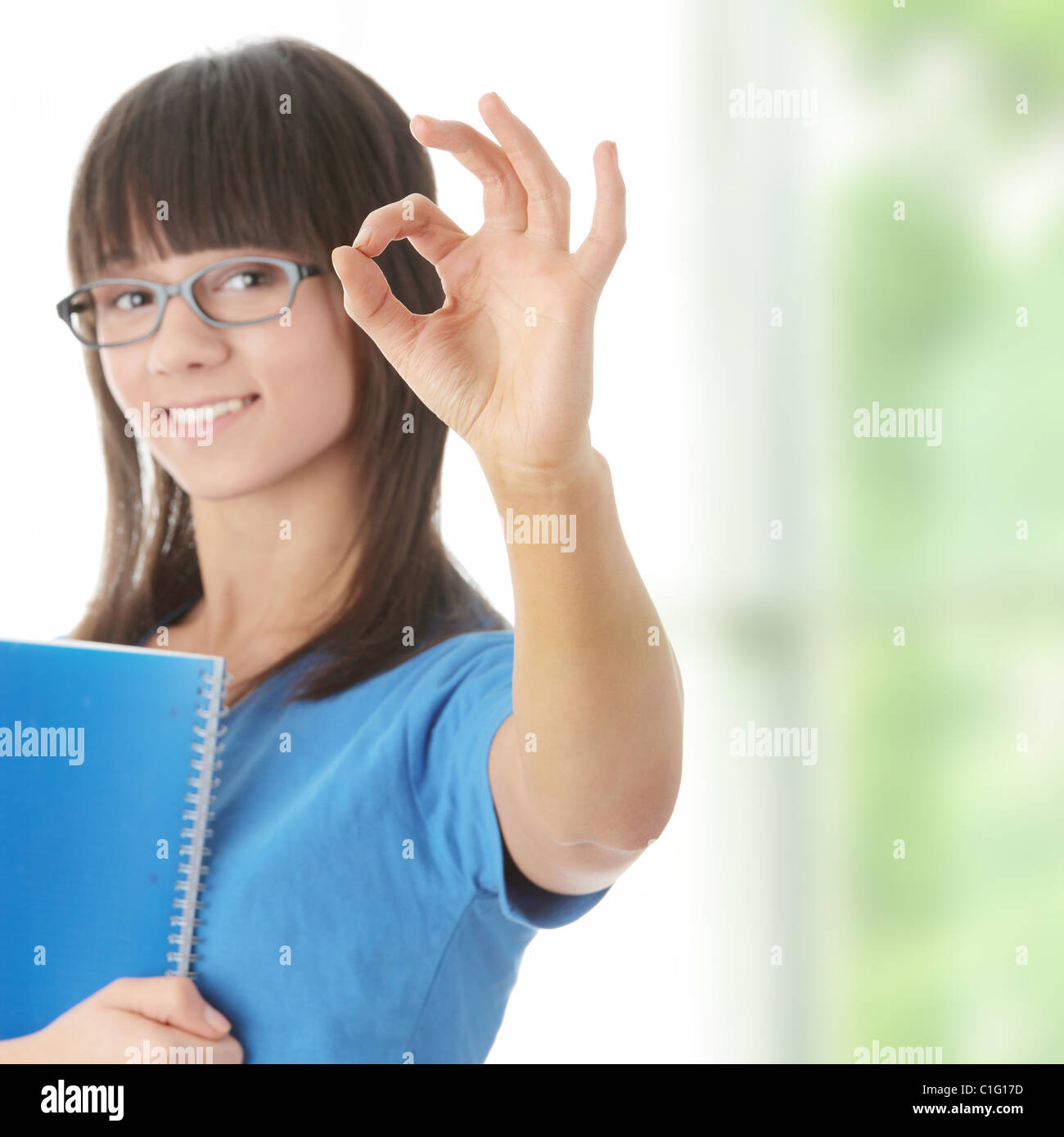 Teen student girl with note pad gesturing OK Stock Photo - Alamy