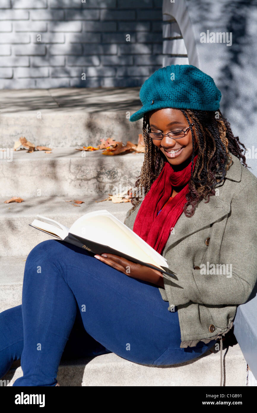 Black woman reading book on front stoop Stock Photo - Alamy