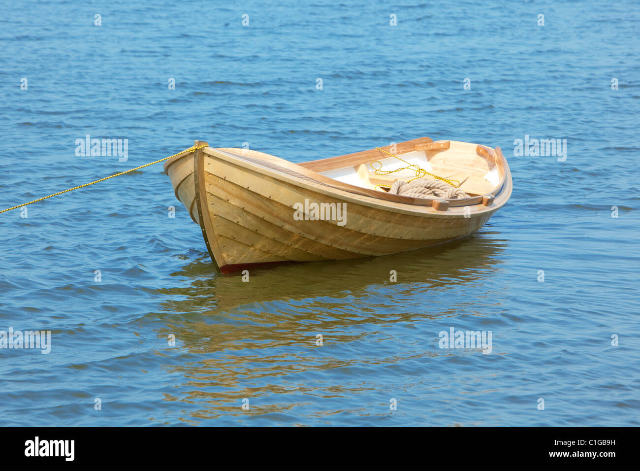 empty fishing wooden new boat on a blue water surface on sunny day ...