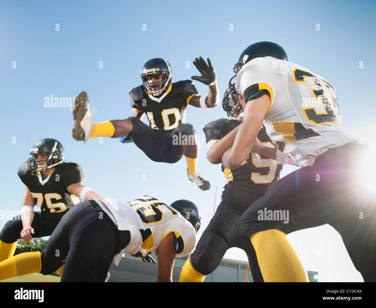 Football player leaping over players on football field Stock Photo - Alamy