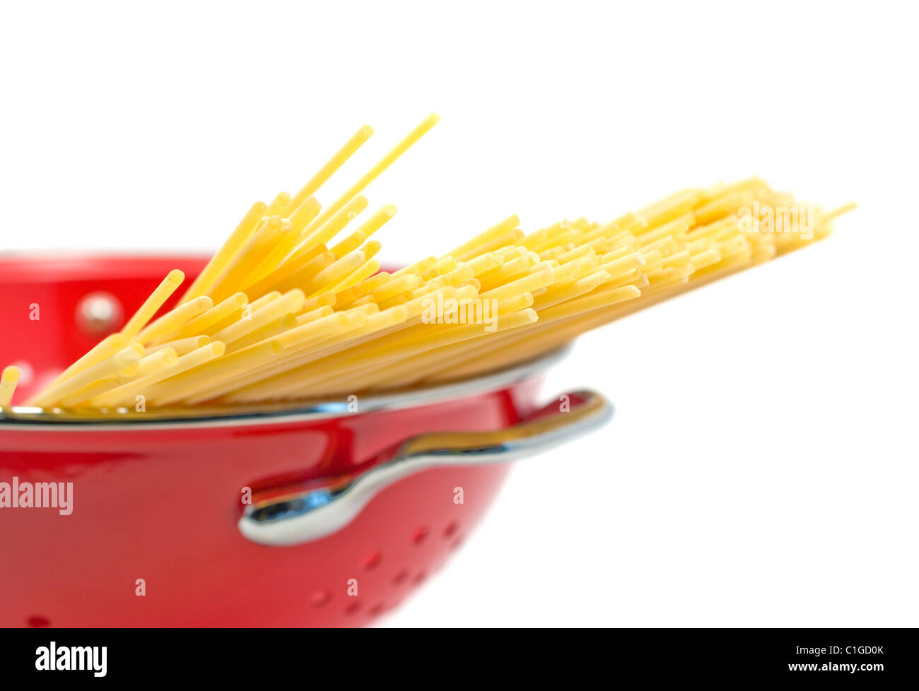 Raw spaghetti in strainer over white background Stock Photo - Alamy