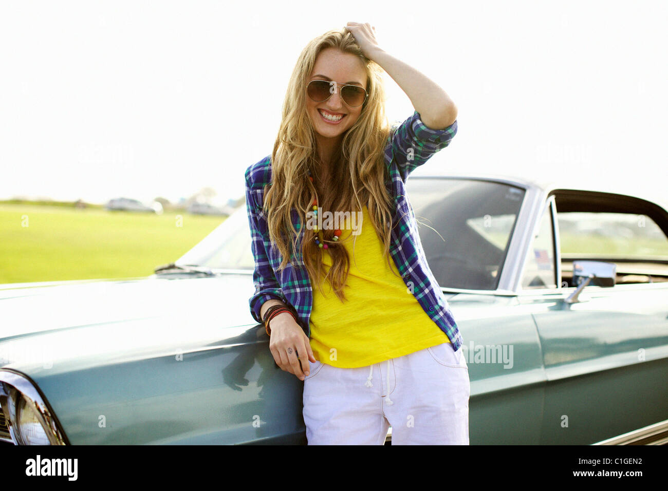 Smiling Caucasian woman leaning against car Stock Photo - Alamy