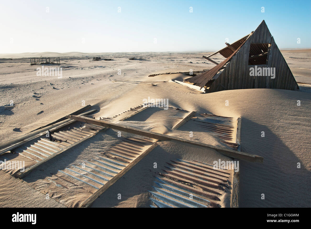Sand dunes cover the remains of an old mining town. Namib desert. Namib ...