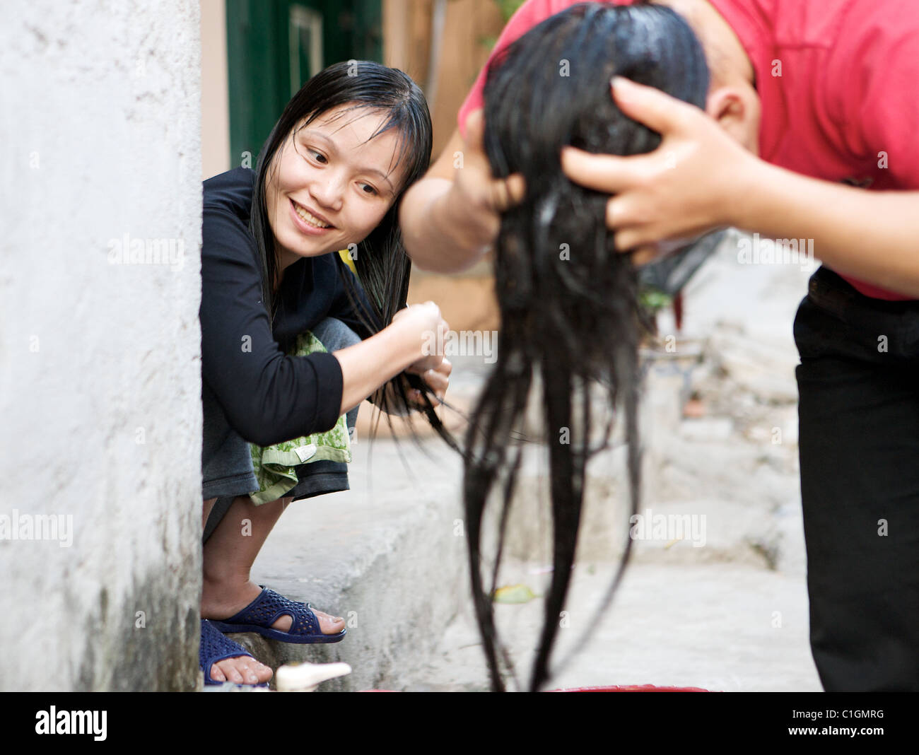Two young girls wash their hair by the railway track that runs through ...