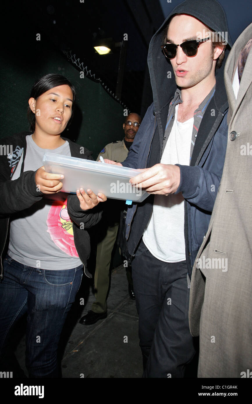 Robert Pattinson signs an autograph for a fan as he arrives at LAX ...