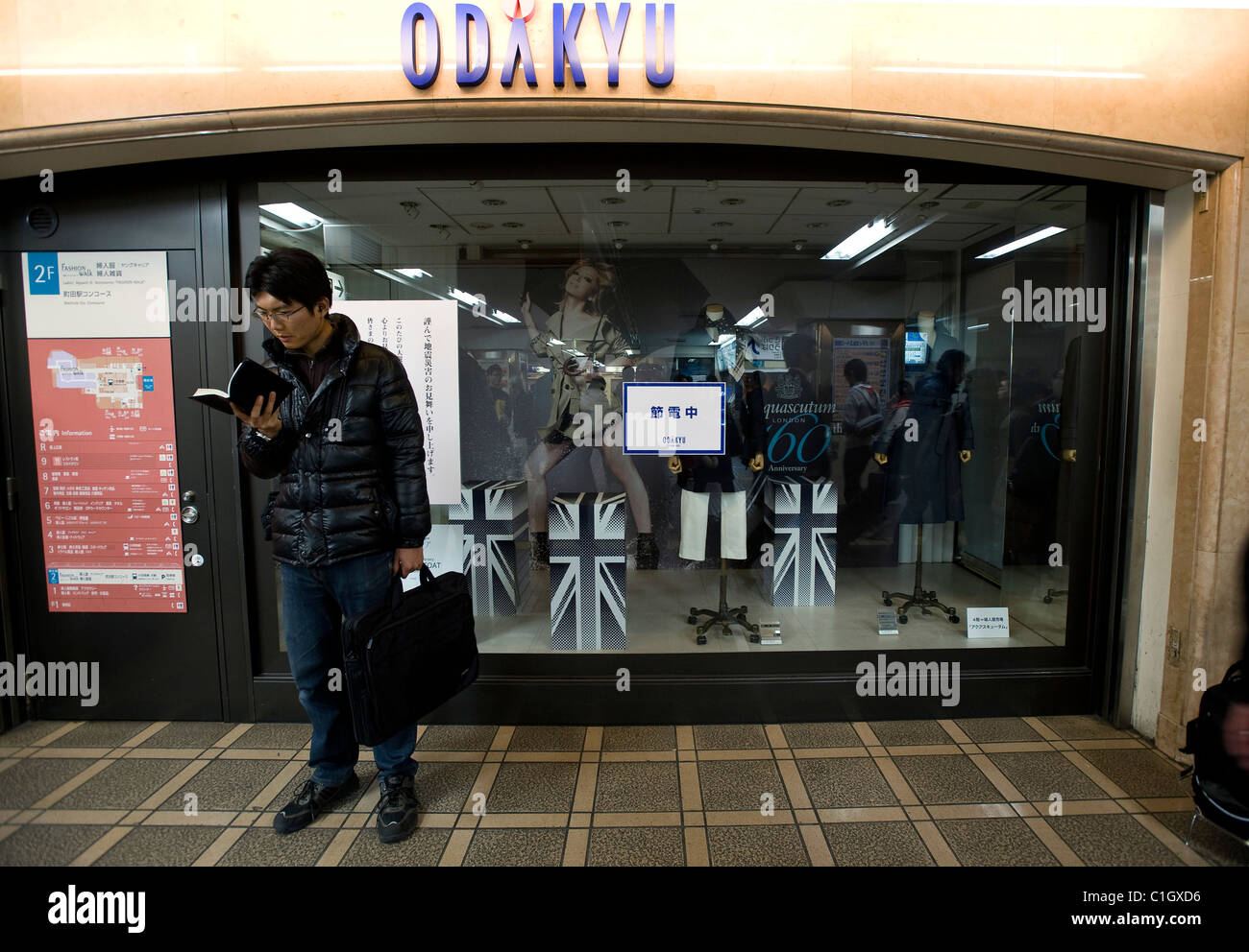 A man reads a book outside a department store that has switched off its ...
