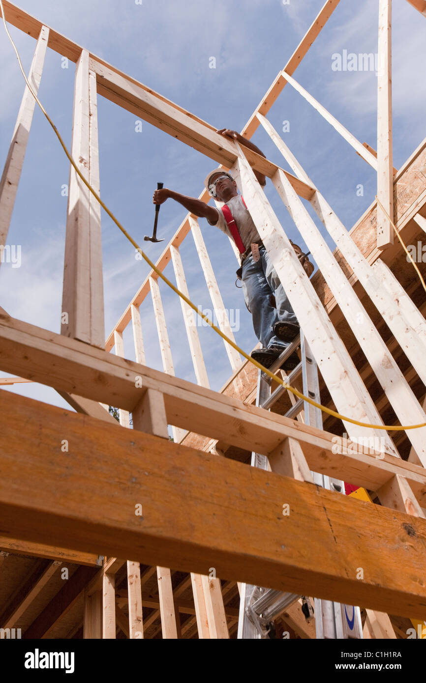 Carpenter using a hammer on the wall frame on the second floor of a ...