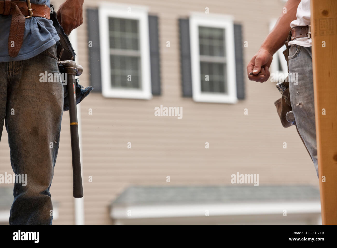 Two carpenters with tool belts at a house under construction Stock ...