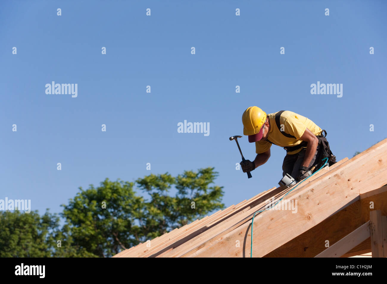 Carpenter hammering on roof rafters Stock Photo - Alamy