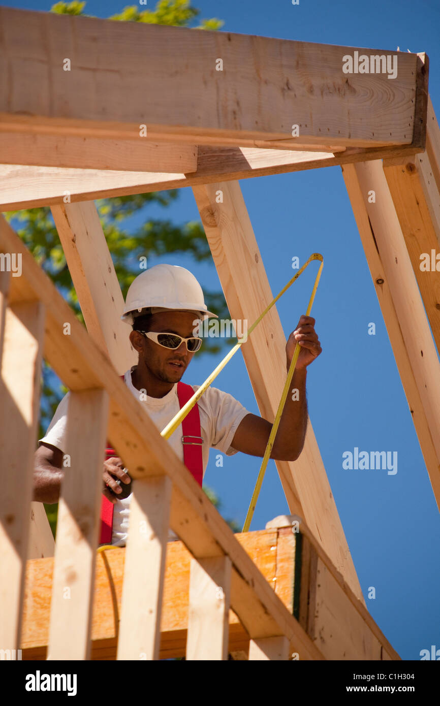 Low angle view of a carpenter measuring roof studs Stock Photo - Alamy