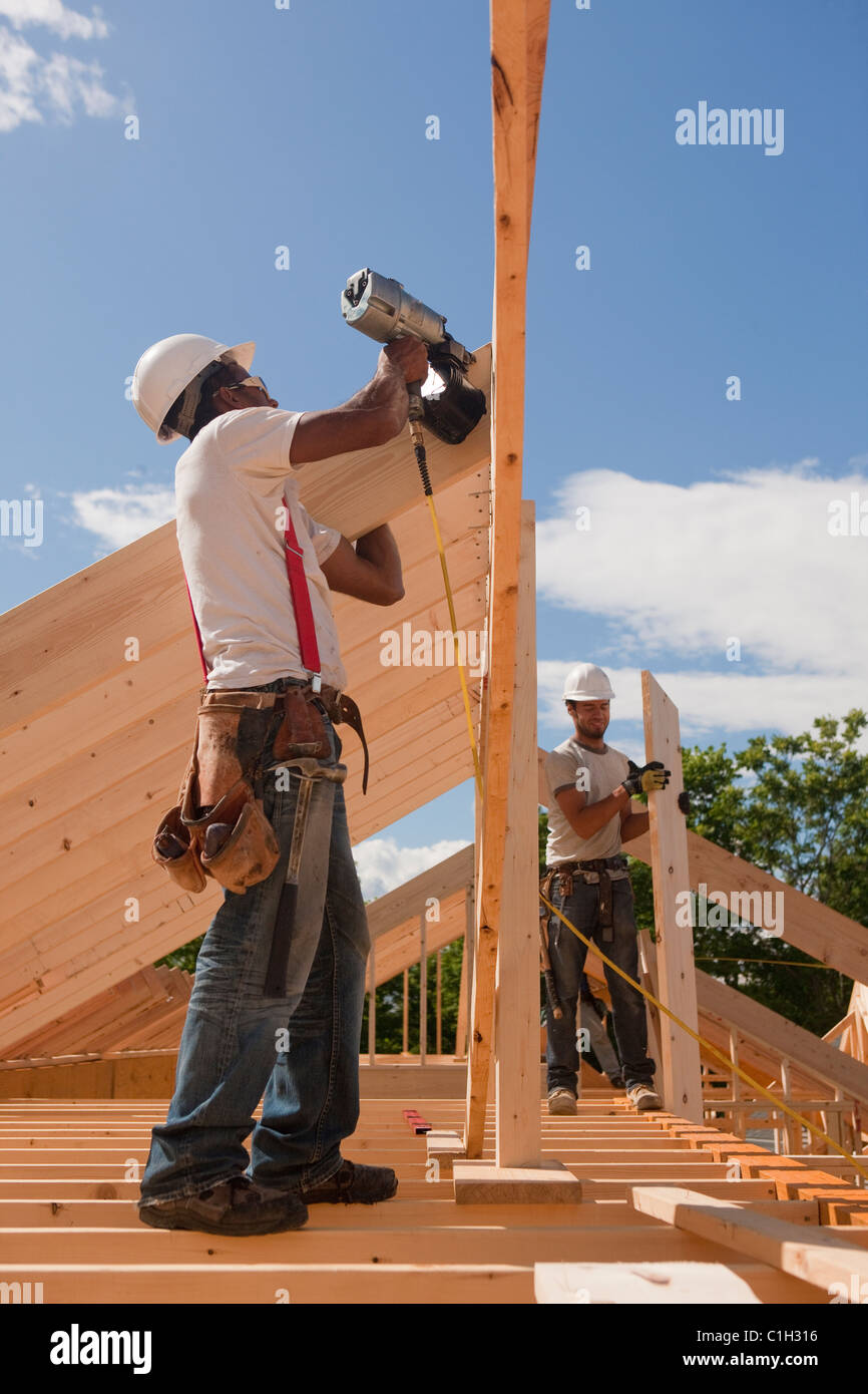 Carpenters nailing and adjusting roof rafters Stock Photo - Alamy