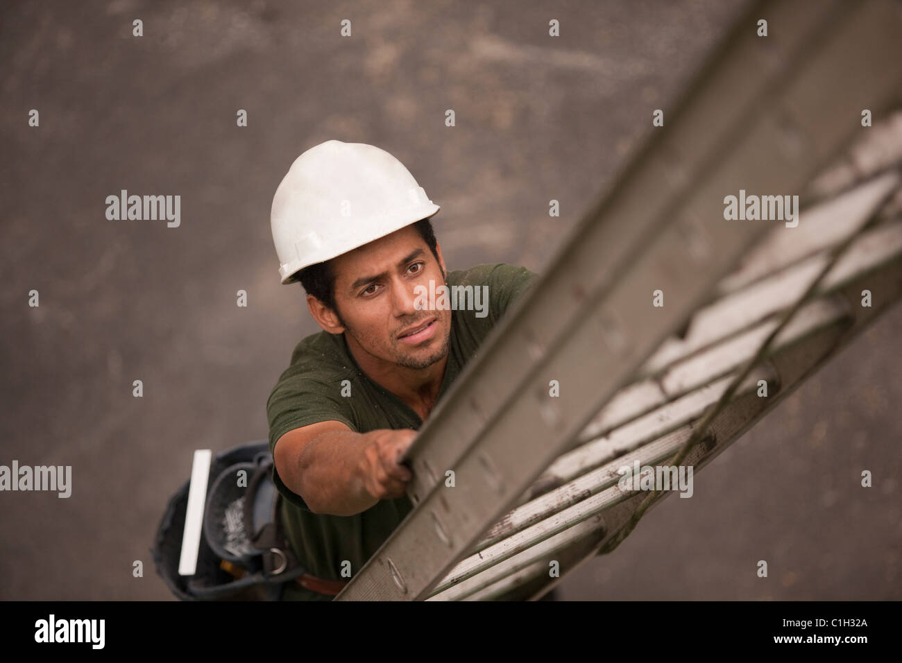 High angle view of a carpenter climbing a ladder at a construction site ...