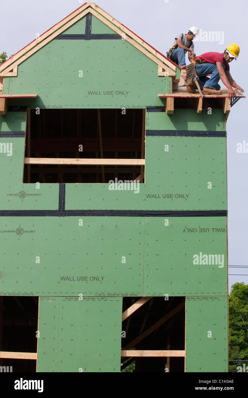 Hispanic carpenters at roof edge measuring to trim Stock Photo - Alamy