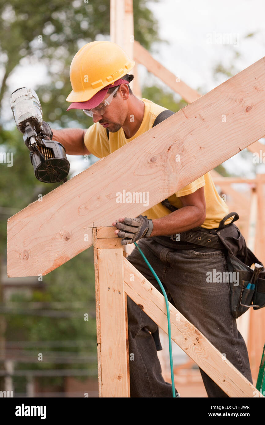 Carpenter nailing rafters to side wall Stock Photo - Alamy