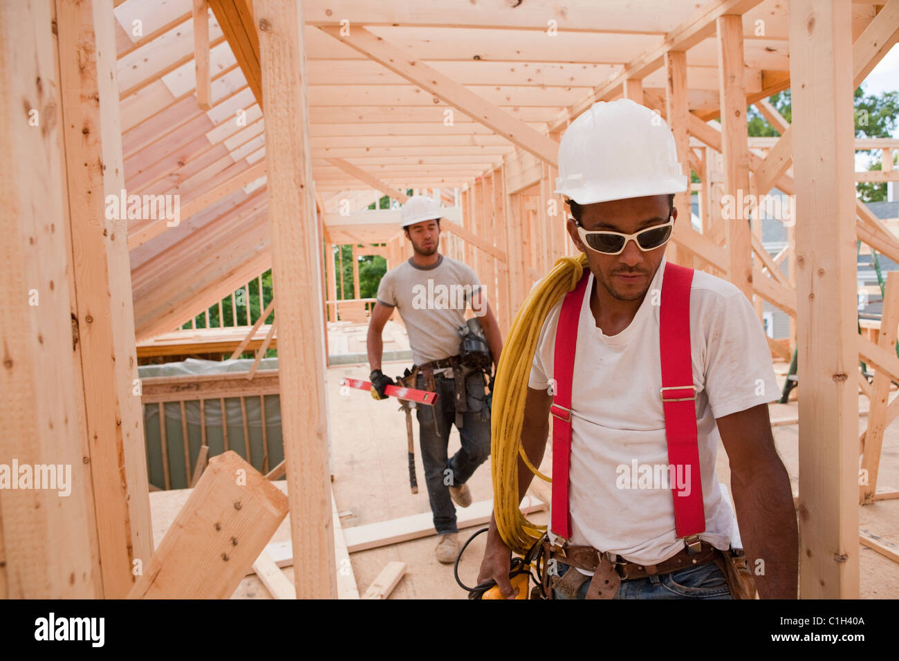 Carpenters holding power cord and level at construction site Stock ...