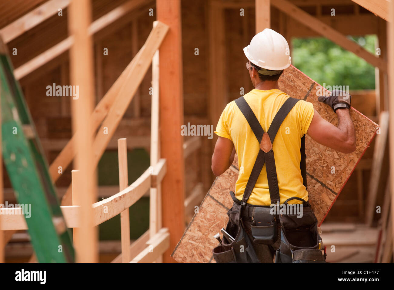 Hispanic carpenter holding a roof panel at a house under construction ...