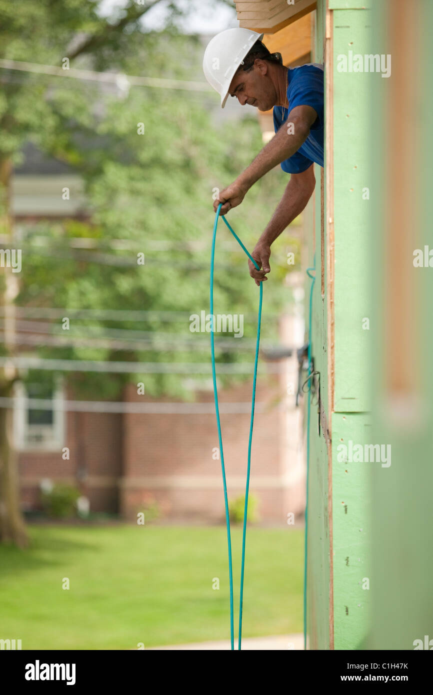 Hispanic carpenter pulling up tools to upper floor at a house under ...
