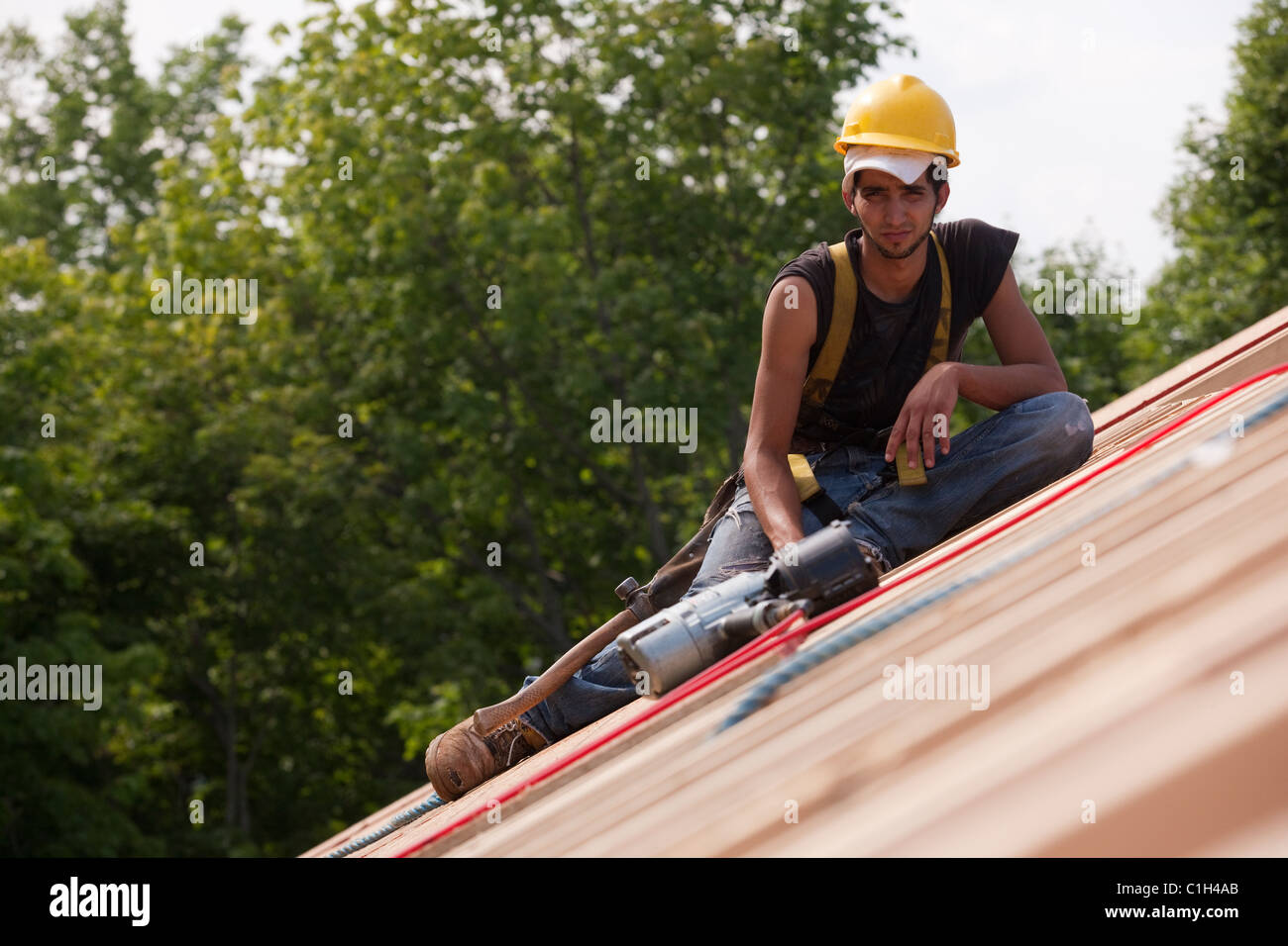 Hispanic carpenter resting on the roof construction of a house with a ...