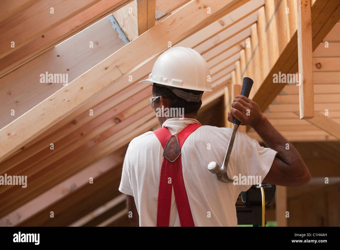 Hispanic carpenter using hammer on upper floor at a house under ...