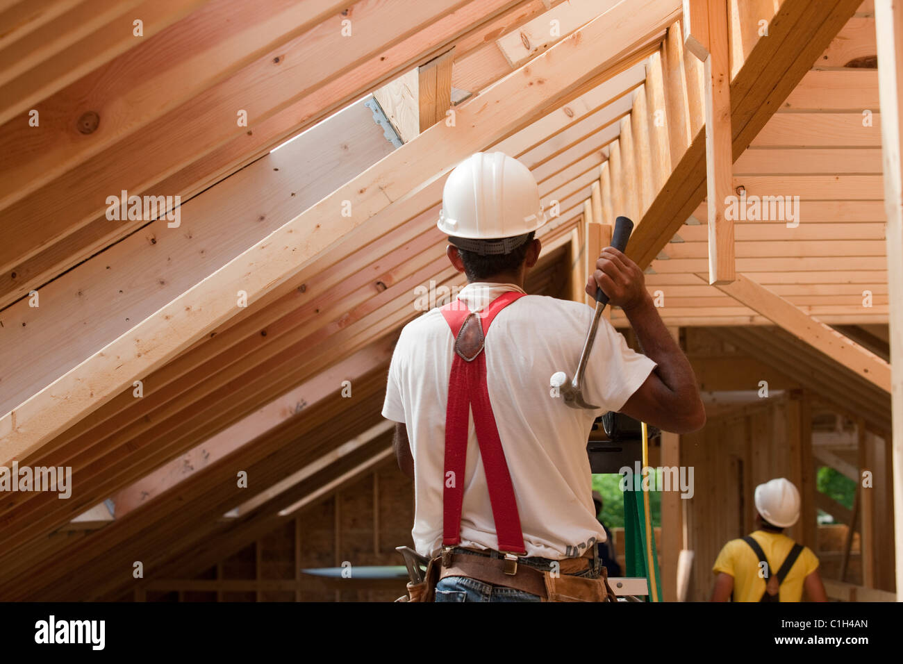 Hispanic carpenter using hammer on upper floor at a house under ...
