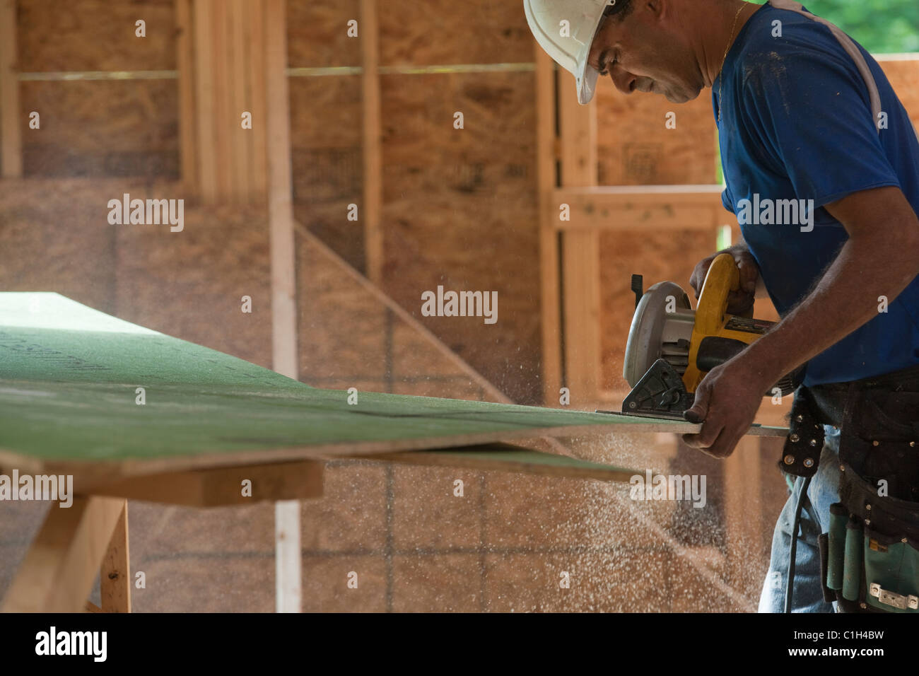 Carpenter cutting exterior sheathing with circular saw at a house under ...