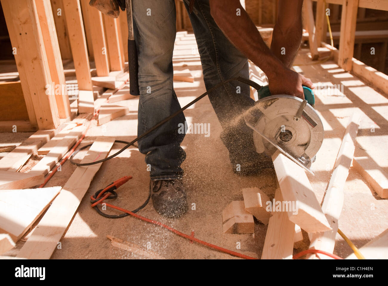 Hispanic carpenter using circular saw on board at a construction site ...