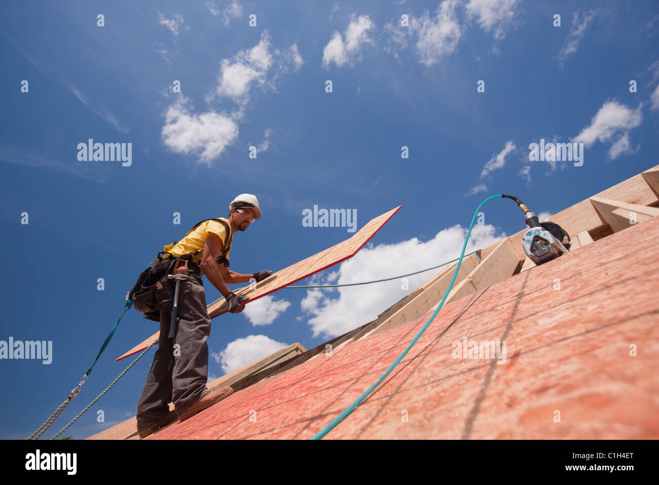 Carpenter installing 'L' shape panel on the roof of a house under ...