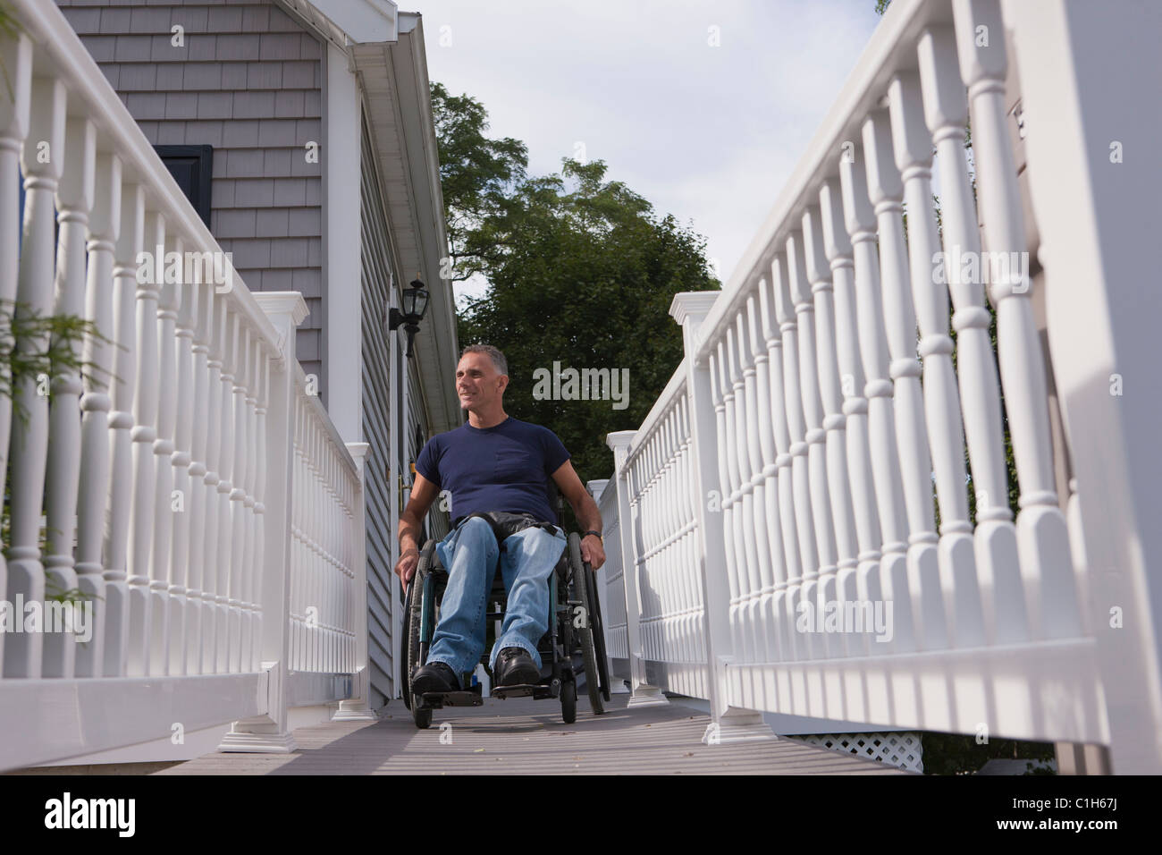 Man with spinal cord injury in a wheelchair on the top of home access ...