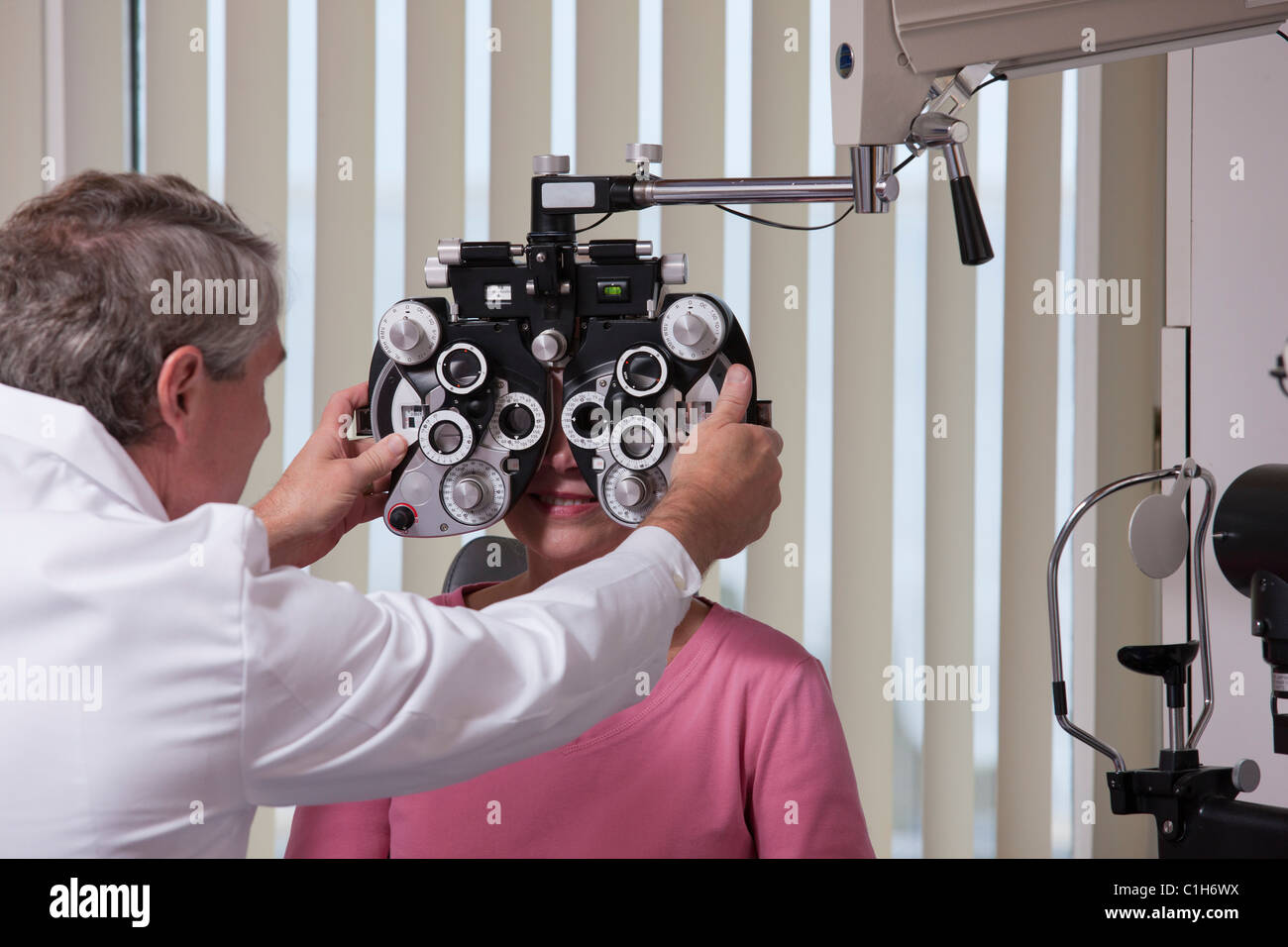 Ophthalmologist placing phoropter in front of a female patient Stock ...