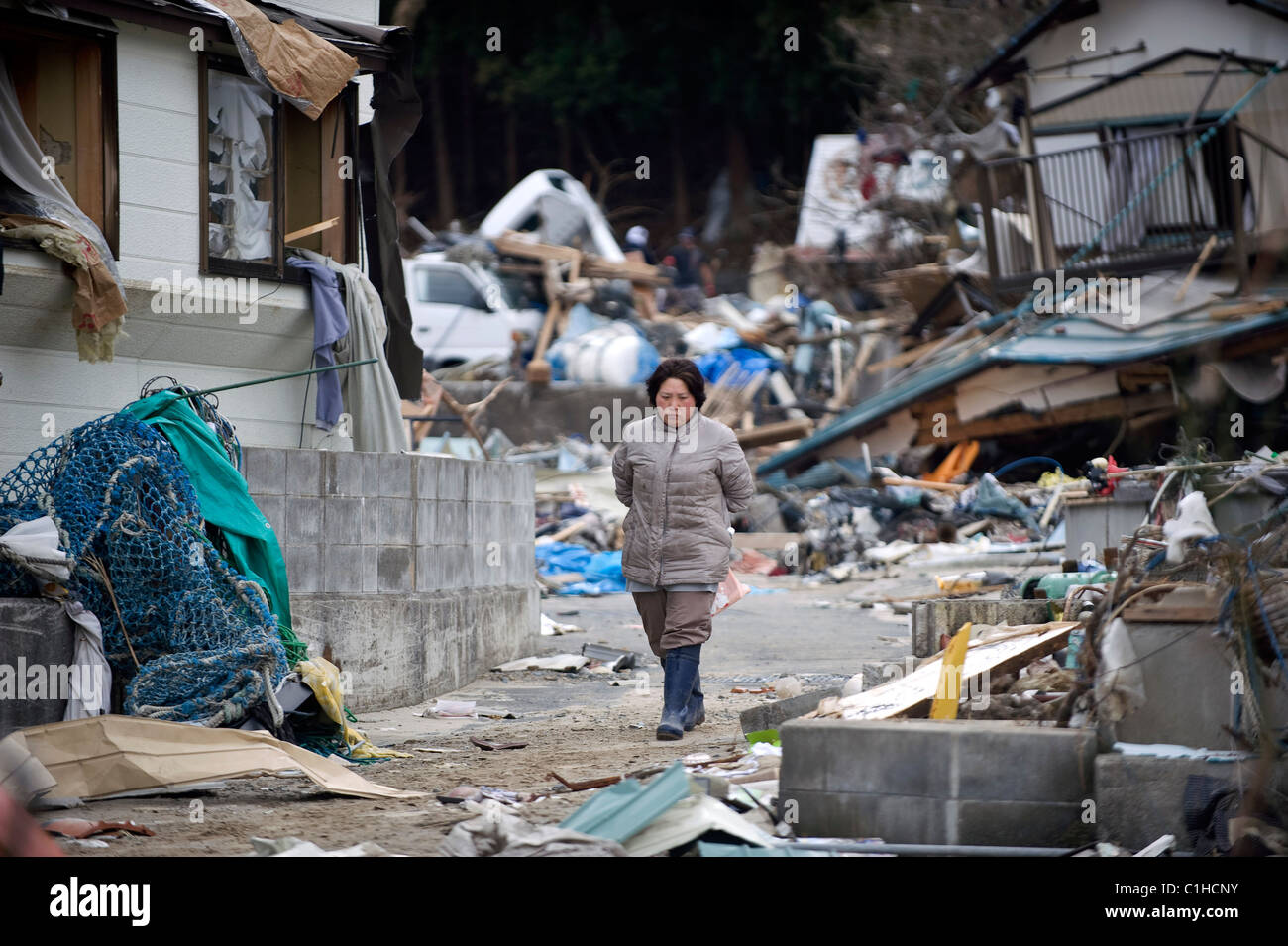 Yoko Abe walks past the wrecked remains of her family's home at Imeshi ...