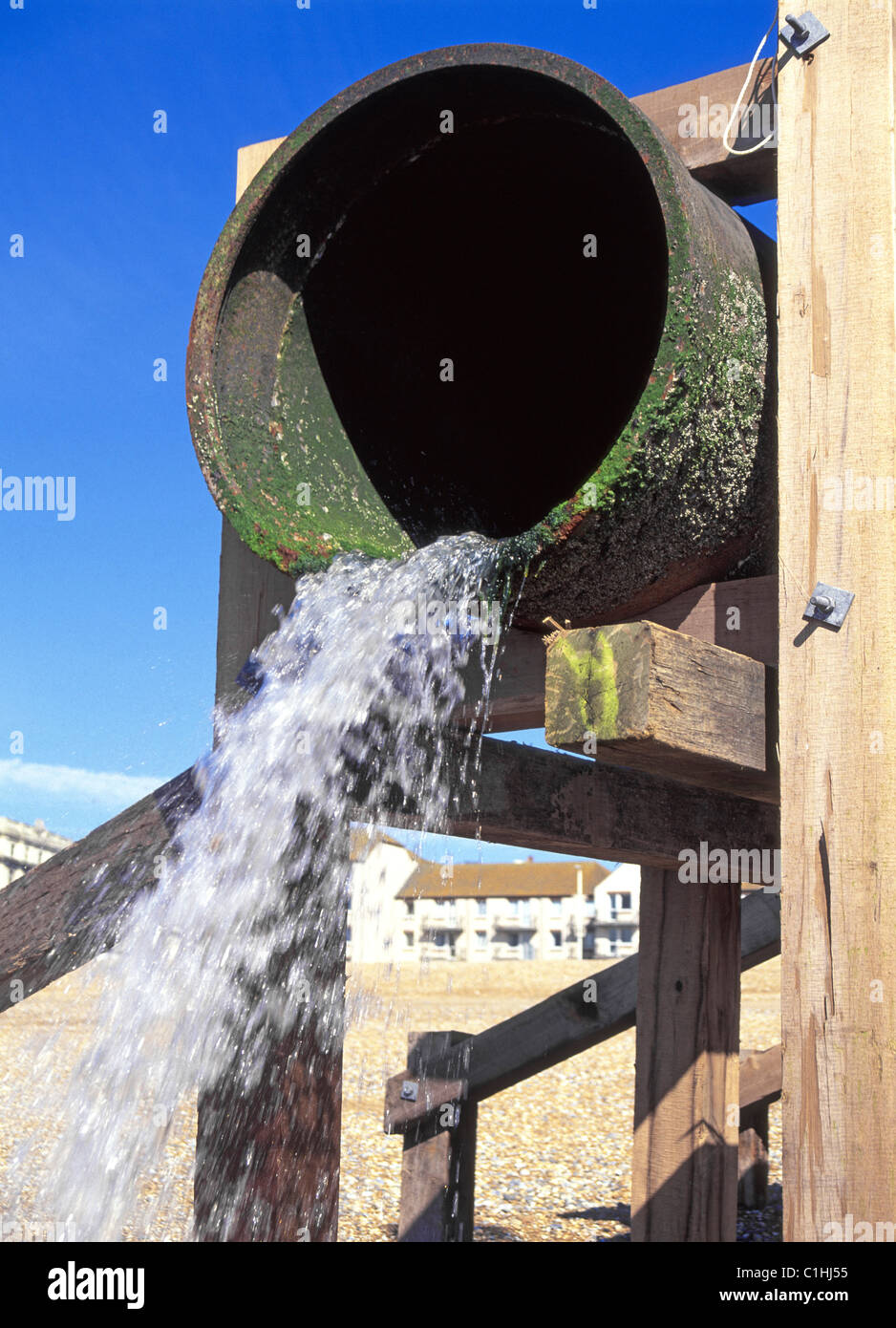 Close up large diameter water outfall drain pipe discharging on beach ...