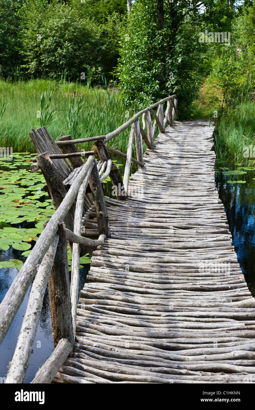 Wooden bridge over river with a bench to rest Stock Photo - Alamy