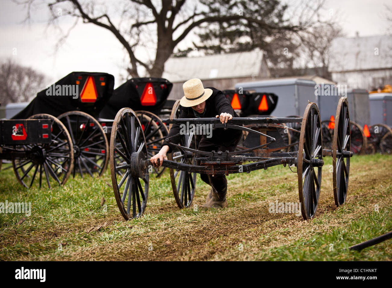 Amish man pushes a buggy ready for auction during the Annual Mud Sale ...