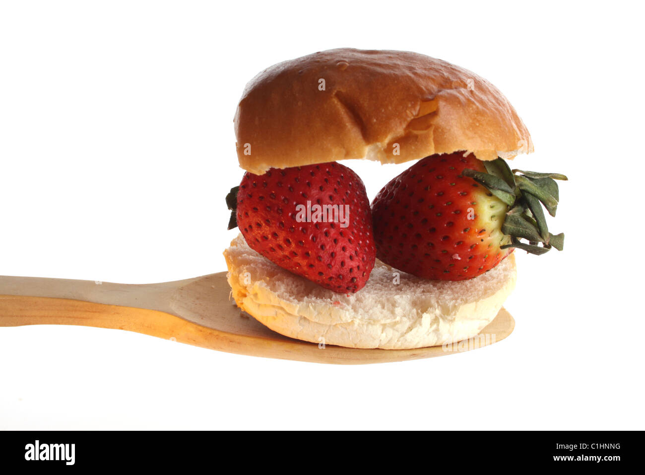 Strawberries on a bread roll wooden spoon against a white background ...