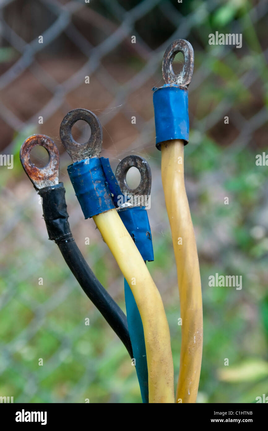 bare electricity cable connectors by the roadside, wire fence backdrop ...