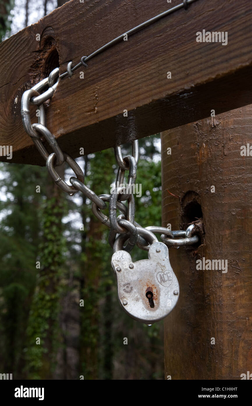 Large metal padlock securing a chain, which is keeping a wooden gate ...