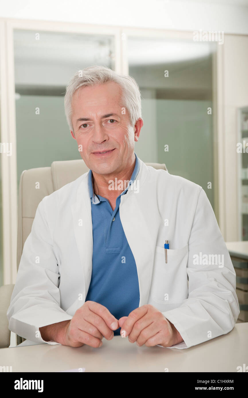 Doctor sitting behind desk Stock Photo - Alamy