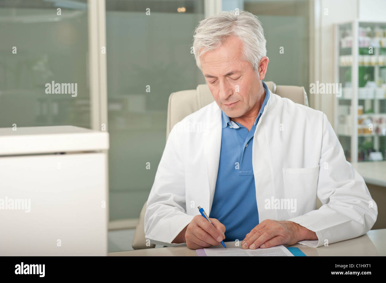 Doctor writing at desk Stock Photo - Alamy