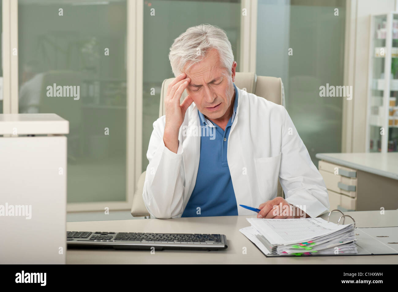 Doctor at desk head in hands Stock Photo - Alamy