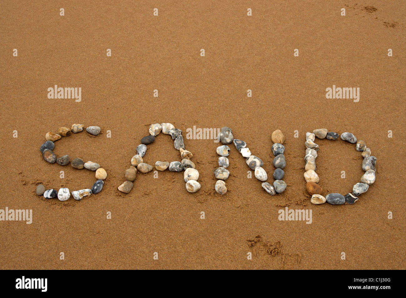 Sand in Stone writing beach sea sand seaside Stock Photo - Alamy