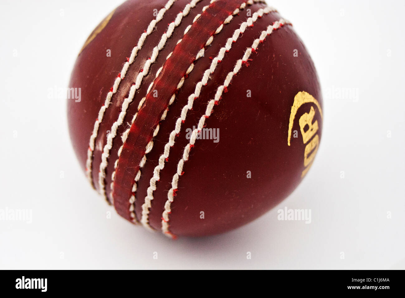 a cropped shot of a dark red cricket ball against clean white ...