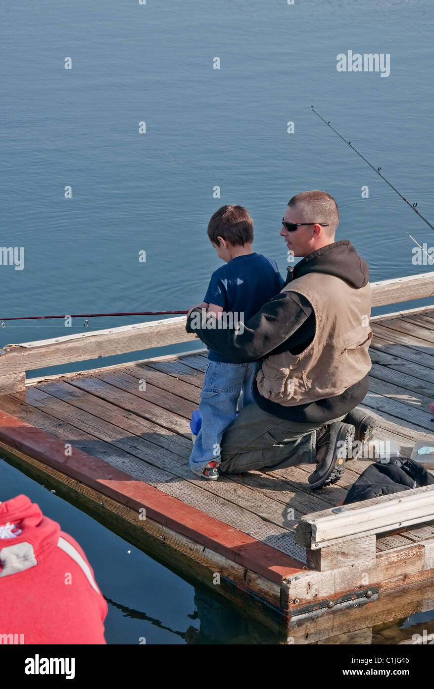 This young father is helping his young son to fish on a dock. This was ...