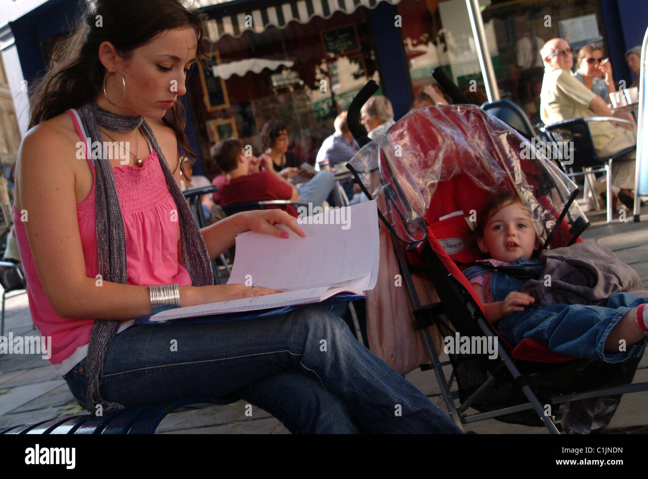 Young female student and looking at paperwork while her child sits in a ...