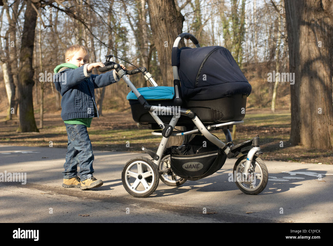 Child blond boy pushing stroller with sister in park Stock Photo - Alamy