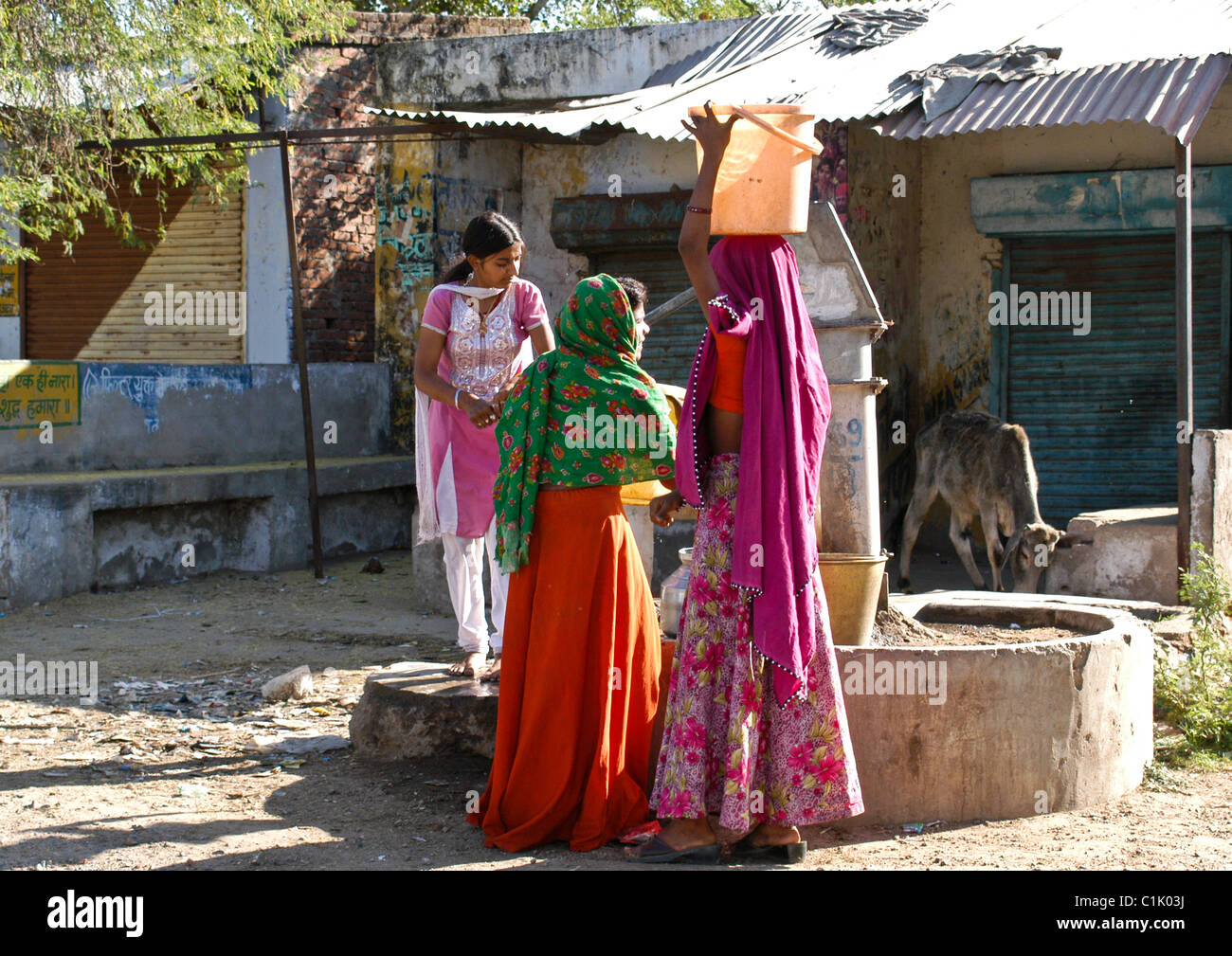 Pretty young village women manually operating a pump to draw fresh ...