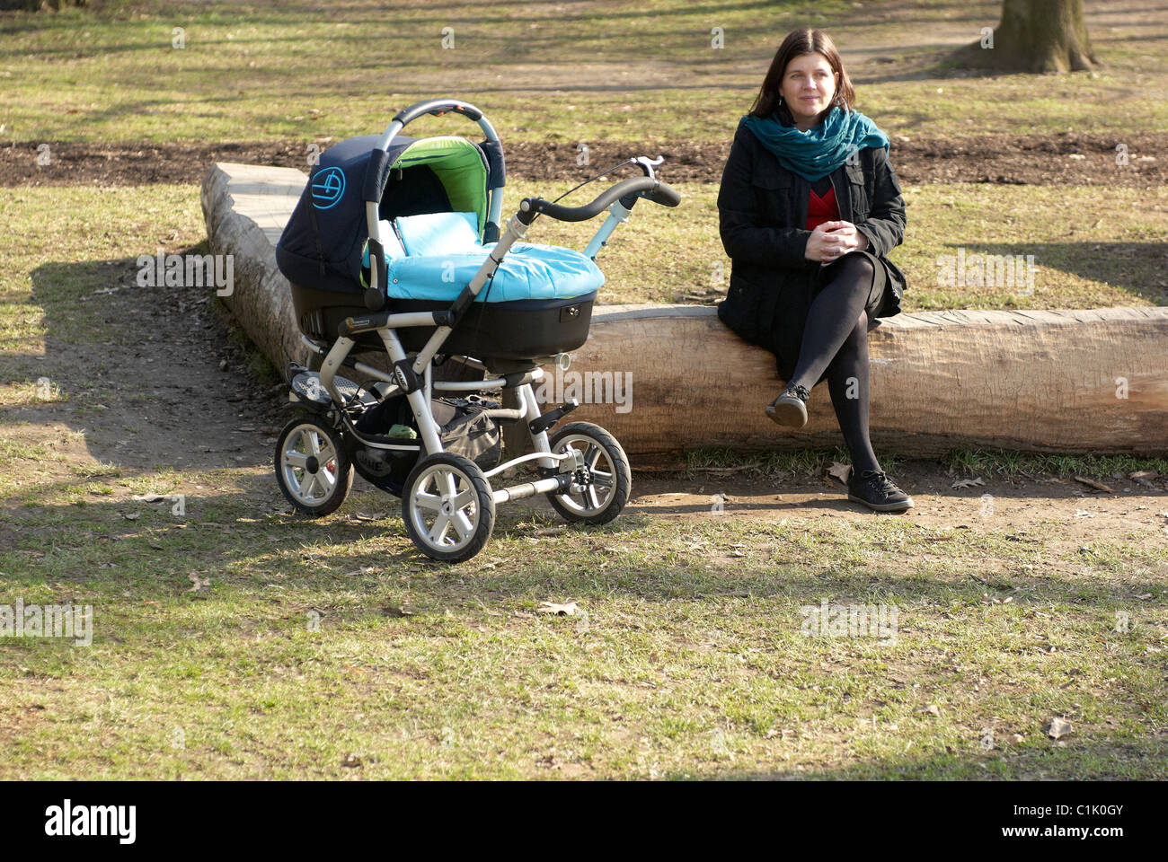 A mother with pushing pram on a bench, spring park Stock Photo - Alamy