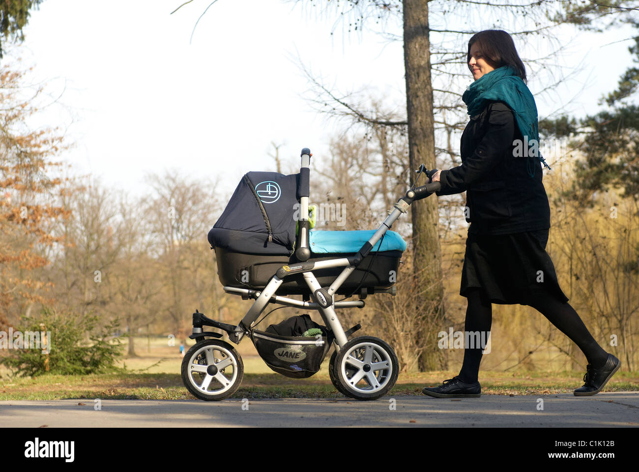 A mother with pushing pram on a bench, spring park Stock Photo - Alamy
