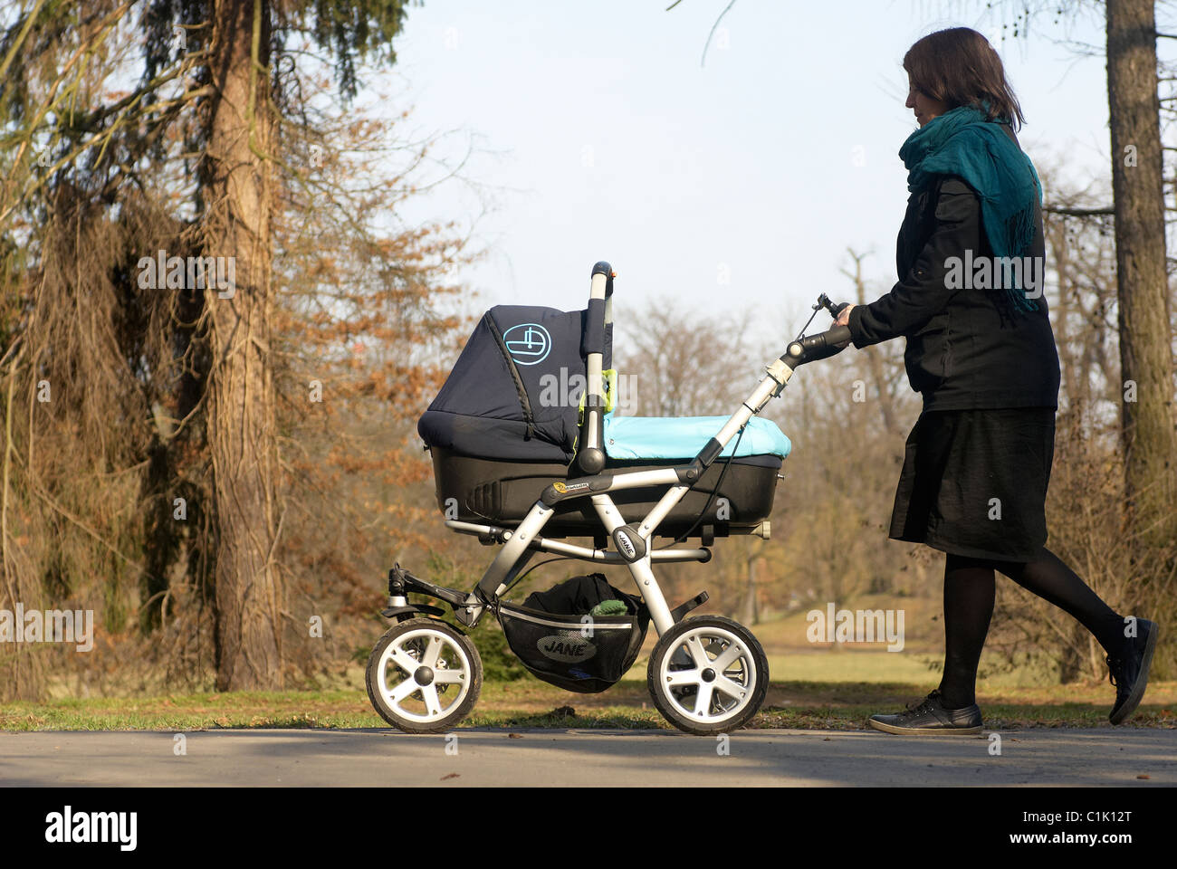A mother with pushing pram on a bench, spring park Stock Photo - Alamy